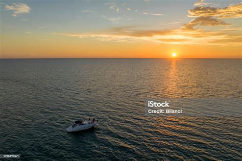 잔물결 표면이 있는 바다 파도에 떠 있는 일몰에 흰색 요트에서 즐거운 시간을 보내는 알아볼 수 없는 사람들의 공중 보기 바다 표면에서 모터 보트 레크리에이션 관광에 대한