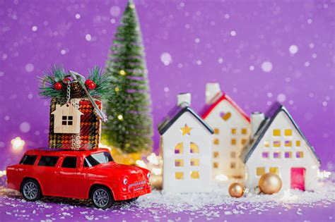 눈 위에 빨간 복고풍 자동차요정 조명 크리스마스 트리와 지붕 과거 주택에 키 체인 별장홈 키와 선물 상자를 운반합니다 보라색 배경 아늑한 새해 부동산 이전 모기지 가정