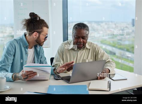A Young Teacher Explaining To Senior Student How Do Computer