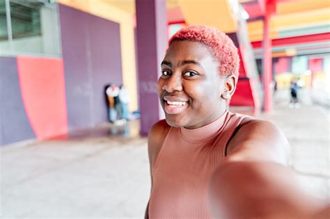 아프리카 계 미국인 여성이 젊은이들과 함께 지하 도시 대안 장소에서 스마트 폰으로 셀카를 찍습니다 Brand Name Smart