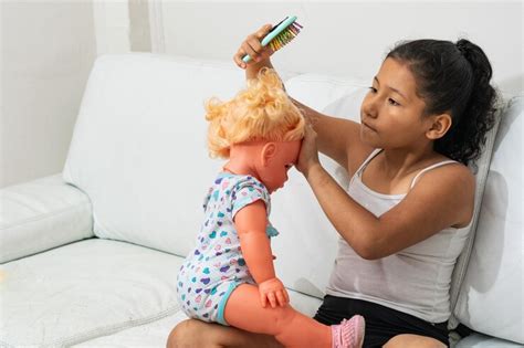 Premium Photo Brunette Girl Playing With Her Doll Combing Her Hair