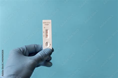 Hand Wearing In Glove Holding Positive Test Result By Using Rapid Test Device For COVID 19 Stock