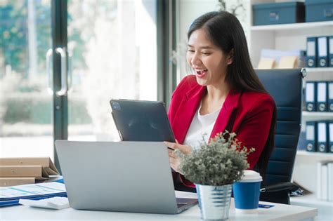 한 젊은 아시아 여성이 낮에는 밝은 사무실의 책상에서 열심히 일합니다 파일 차트 및 장치에 둘러싸인 그녀는 마케팅 퍼널 및 Seo 최적화에 대한 전략을 수립합니다 25 29