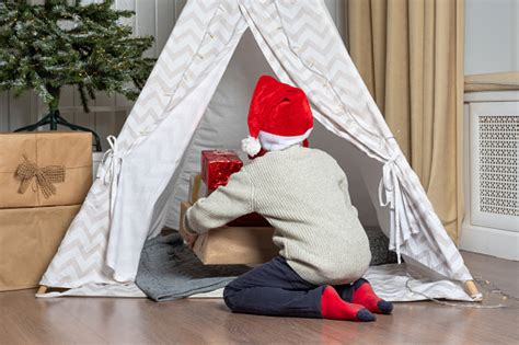 산타 모자를 쓴 미취학 아동 소년이 보육원의 어린이 텐트 가발에 선물을 숨 깁니다 아이는 혼자 있고 싶어 12월에 대한 스톡 사진 및 기타 이미지 Istock