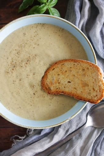 파란색과 흰색 줄무늬 티 타월 건강한 식용 다이어트 음식 높은 전망 외에 구운 흰 빵 조각과 함께 금이 간 검은 후추로 양념 한 수제 부추와 감자 수프의 옅은 파란색 그릇의