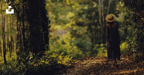 낮 동안 숲에 서 있는 갈색 모자를 쓴 검은 드레스를 입은 여자 사진 Unsplash의 무료 의복 이미지