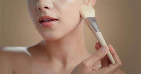 여성 입 브러시는 스튜디오에서 메이크업 화장품 도포 아름다움에 자신감이 있습니다 소녀 입술과 홍당무는 파우더 맑은 피부와 자기 관리를 위한 얼굴 갈색 배경에 25 29세에