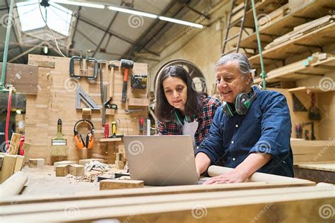 Experienced Craftsman Mentoring Apprentice In A Busy Lumberyard Workshop Stock Image Image Of