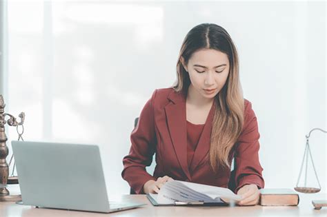 여성 변호사 또는 판사가 문서나 계약서를 확인하고 수첩에 메모를 하고 법률 사무소에서 망치와 저울을 들고 노트북을 옆에 두고 일하고 있습니다 Conference On The