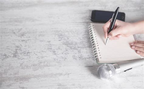 Girl Writing On Notepad Microphone And Smartphone On The Desk Stock