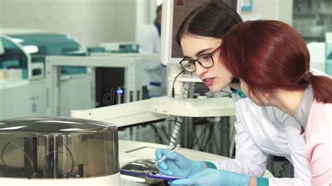 Close Up Of Two Female Biologists Making Notes While Conducting