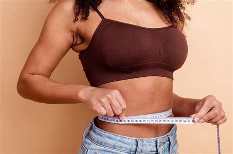 베이지색 배경에 건강하고 몸매가 좋은 라이프스타일을 보여주는 줄자로 허리를 재는 젊은 여성 25 29세에 대한 스톡 사진 및 기타 이미지 25 29세 건강관리와 의술