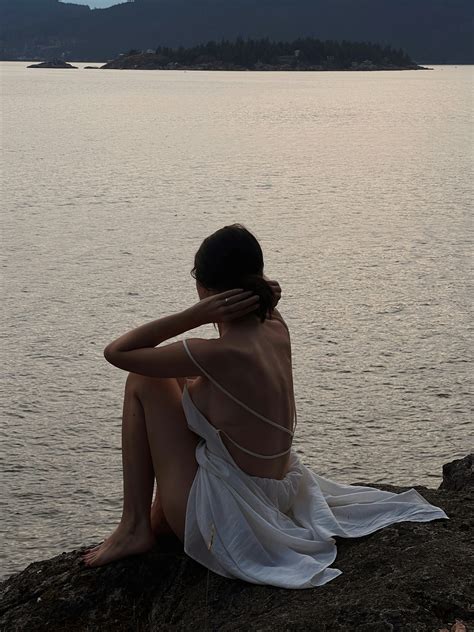 A Woman Sitting On A Rock Looking Out At The Water Photo Free Woman