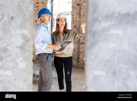 Female Client Gesturing While Discussing With Male Architect At Construction Site Stock Photo