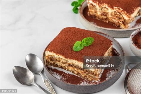접시에 담긴 전통 이탈리아 디저트 티라미수 신선한 민트와 숟가락을 곁들인 수제 티라미수 케이크 부분 티라미수에 대한 스톡 사진