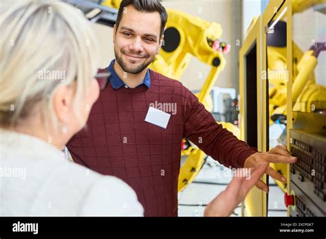 Engineers Having A Conversation While Programming A Robot The Image Depicts Teamwork And