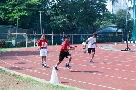 A Group Of Young Men Running Around A Track Photo Free Human Image On