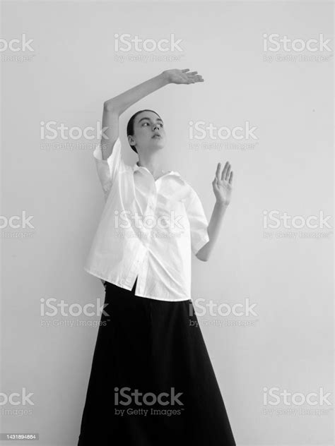 세련 된 미니멀리즘 옷을 입고 아름 다운 젊은 여자 스칸디나비아 스타일 화이트 반 소매 셔츠 긴 넓은 검은 맥시 스커트 패션 모델 포즈를 취하는 표현 자신감 있는 예쁜 패션