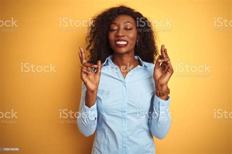 고립 된 노란색 배경 제스처 손가락 위에 우아한 셔츠를 입고 아프리카 계 미국인 사업가는 희망과 눈을 감고 미소를 교차 행운과 미신 개념 경영자에 대한 스톡 사진 및 기타