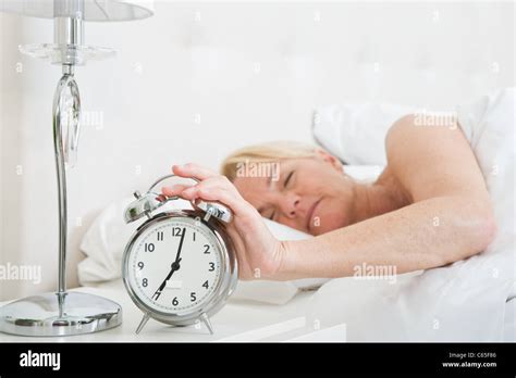 Woman In Bed Turning Off Alarm Stock Photo Alamy