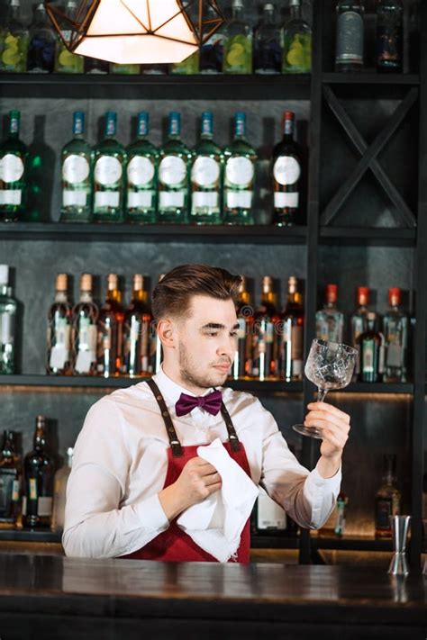 Bartender Standing At Bar Counter Cleaning Glasses With Towel Stock