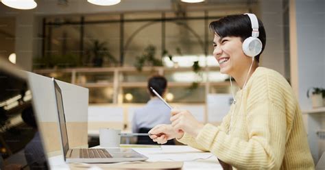 헤드폰을 끼고 노트북 앞 책상 옆에 앉아 음악을 듣고 즐거운 시간을 보내는 젊은 사무실 관리자 사진 Unsplash의 헤드폰 이미지