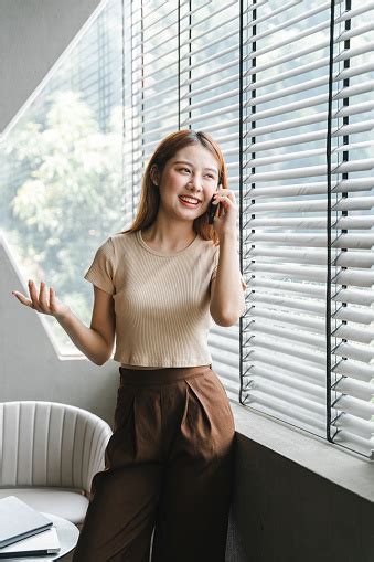 아시아 소녀 아름다운 여자는 창문 옆의 집에서 전화로 이야기하는 것을 즐깁니다 18 19세에 대한 스톡 사진 및 기타 이미지 18 19세 20 29세 30 39세