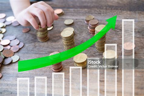 작은 아이는 금속 동전으로 조작하고 아이는 세고 유로 연합 돈을 테이블에 놓고 성장 그래프와 위쪽 화살표의 할로그램 방향 개발의 성장 개념 용돈 생명 보험 그래프에 대한