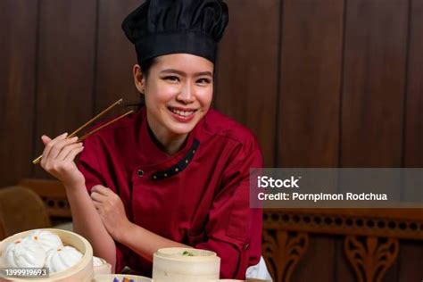 초상화 아름다운 전통 전문 중국 요리사가 빨간 유니폼 모자를 쓰고 행복하게 웃고 젓가락을 들고 광고를위한 음식 바구니를 제시합니다 레스토랑 음식 호텔 컨셉 고급 요리에 대한