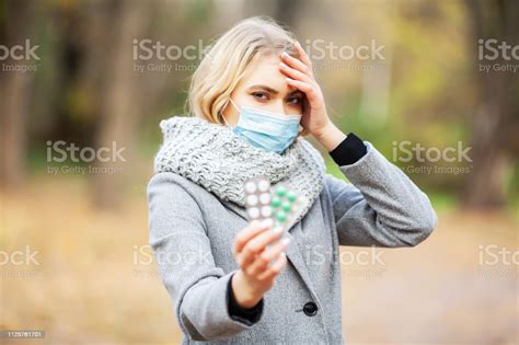 차가운가 여자 얼굴 마스크를 착용 하 고 공원에서 피 나무 중에서 알 약을 들고 건강관리와 의술에 대한 스톡 사진 및 기타 이미지 건강관리와 의술 계절 과수원