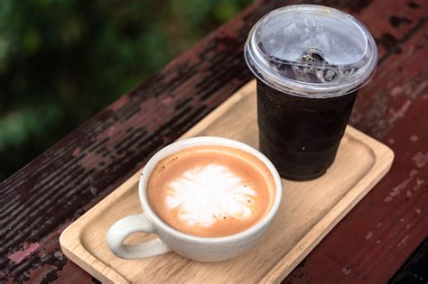 아메리카노 아이스 커피 또는 블랙 커피와 뜨거운 우유 차 안개가 자욱한 숲 아름 다운 풍경 안개 낀 산 자연 배경의 경치 좋은 전망 나무 책상에 컵 0명에 대한 스톡 사진