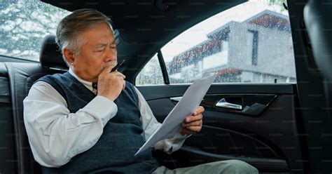 자신감 아시아 고위 사업가는 차 뒷좌석에 앉아 사무실에 가는 동안 사업 계획을 작성합니다 자동차에서 일하며 창밖의 교통을 바라보는 노인 Ceo 사진 Unsplash의