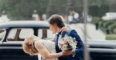결혼식 후 낭만적인 신부와 신랑 초상화 야외에서 춤을 추는 행복한 신혼 커플 배경에 있는 고급 자동차 신부를 껴안고 있는 행복한 신랑 사진 Unsplash의 남자와