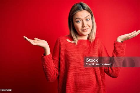 빨간 고립 된 배경 단서와 팔과 손을 제기 혼란 표정을 통해 캐주얼 스웨터를 입고 젊은 아름다운 금발 여성 의심 개념 감정에 대한 스톡 사진 및 기타 이미지 Istock