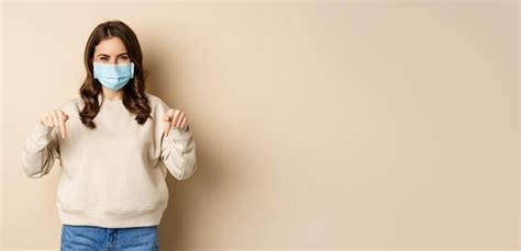 프로텍티오를 사용하여 광고를 보여주는 의료용 얼굴 마스크를 쓴 쾌활한 귀여운 여성 무료 사진