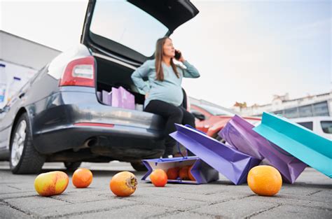 자동차의 열린 트렁크에 앉아 임신 한 여성의 배경에 아스팔트에 흩어져 과일의 하단 보기 30 34세에 대한 스톡 사진 및 기타 이미지 30 34세 가방 가을 Istock