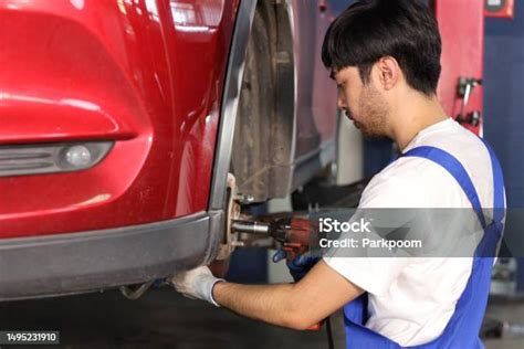 남자 기술자 자동차 정비사는 제복을 입고 수리 차고 역에서 리프트 자동차 서비스를 점검하거나 유지 보수합니다 렌치를 잡고