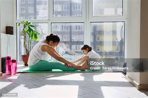 딸과 함께 운동하는 젊은 여성 아름다운 화창한 날에 집에서 큰 창문의 배경에 그녀의 몸을 스트레칭 2 3 살에 대한 스톡 사진 및 기타 이미지 Istock