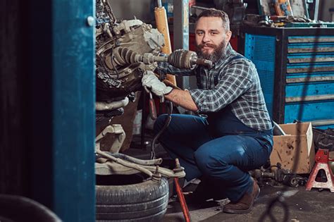잔인 한 문신된 수염된 정비사 전문 차고에서 유압 리프트에 발생 하는 자동차 엔진 수리 서비스 역입니다 금속의에 대한 스톡 사진