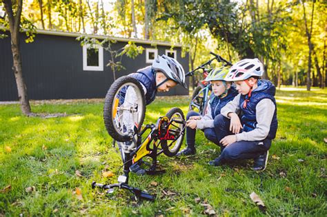 팀웍 큰 가족 세 백인 어린이 형제는 자전거를 수리 하는 학습 공원에서 녹색 잔디에 구축에 대 한 헬멧 같은 옷에 도구를 사용 하 여 가족에 대한 스톡 사진 및 기타 이미지
