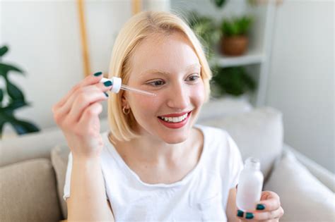 젊은 예쁜 여자는 집에서 특별한 피부 치료를 받고 아름다운 소녀 적용 눈 혈청 주름없이 매끄러운 피부 개념에 대한 스톡 사진 및