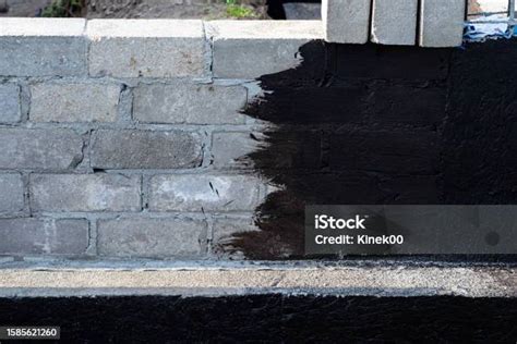 검은 색 분산 아스팔트 고무 덩어리로 칠해진 콘크리트 블록으로 만든 기초 철근 콘크리트 기둥이 보입니다 0명에 대한 스톡 사진