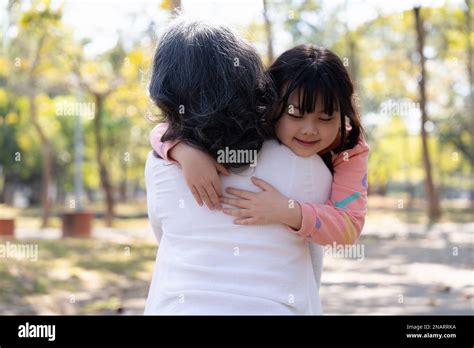 An Cute Granddaughter Giving Hug Cuddling To Her Grandmother Having