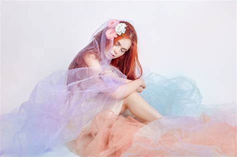 가벼운 공기 색된 드레스에 빨간 머리 소녀 바닥 흰색 배경에서 앉는 다 여자 머리에 아름 다운 꽃입니다 긴 머리와 구름 드레스와