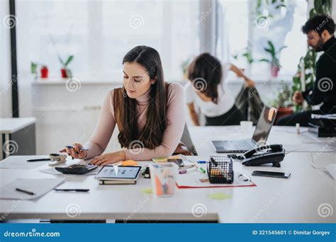 Focused Young Professional Woman Calculating Finances In Busy Modern
