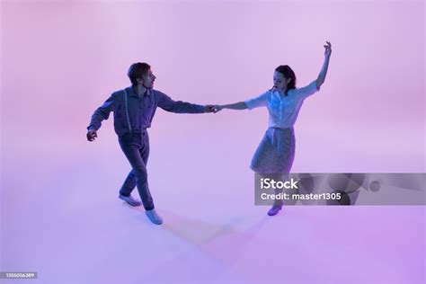댄서의 부부 젊은 남자와 여자 빈티지 복고풍 스타일의 의상 댄스 스윙 댄스 에 라일락 색상 배경 에 네온 빛 1950 1959