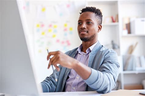 잠겨있는 콘텐츠 젊은 흑인 그래픽 디자이너 수염 컴퓨터에 앉아서 사무실에서 작업 하는 동안 프로젝트의 생각 심각한에 대한 스톡