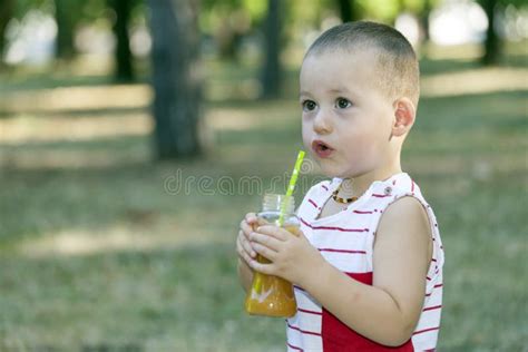 Retrato De Uma Parte Externa Bonito Do Rapaz Pequeno Ao Beber O Suco De Foto De Stock Imagem