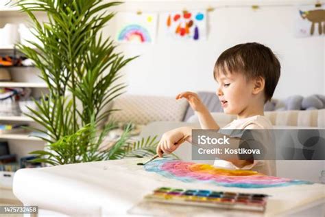 자신감 있는 귀여운 남성 아이 예술 그리기 여러 가지 빛깔의 무지개 아치는 테이블에 페인트와 브러시를 사용합니다 가정 생활에 대한 스톡 사진 및 기타 이미지 Istock