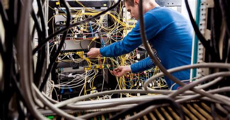 Network Engineer Working In Server Room Connecting Network Cables To Switches Stock Image